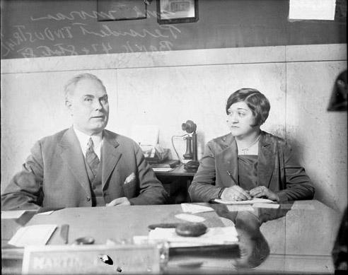ECC | [Mr. Moran sitting next to an unidentified woman at a desk i