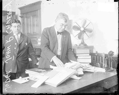 ECC | [Judge Caverly standing and looking at a pile of papers on a