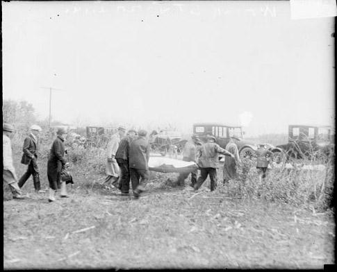 ECC | [Group of men carrying a body on a stretcher, walking across
