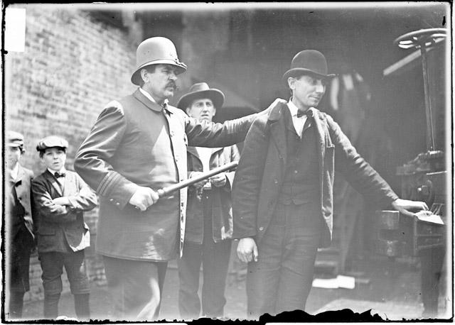 ECC | [Policeman with a billy club leading a man away during the 1