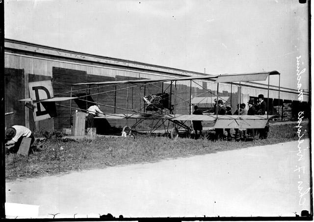 ECC | [Charles F. Willard's airplane parked alongside a low buildi