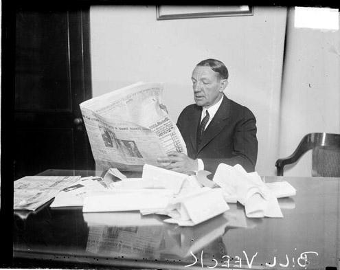 ECC | [Bill Veeck, Sr., president Cubs, reading a newspaper, sitti
